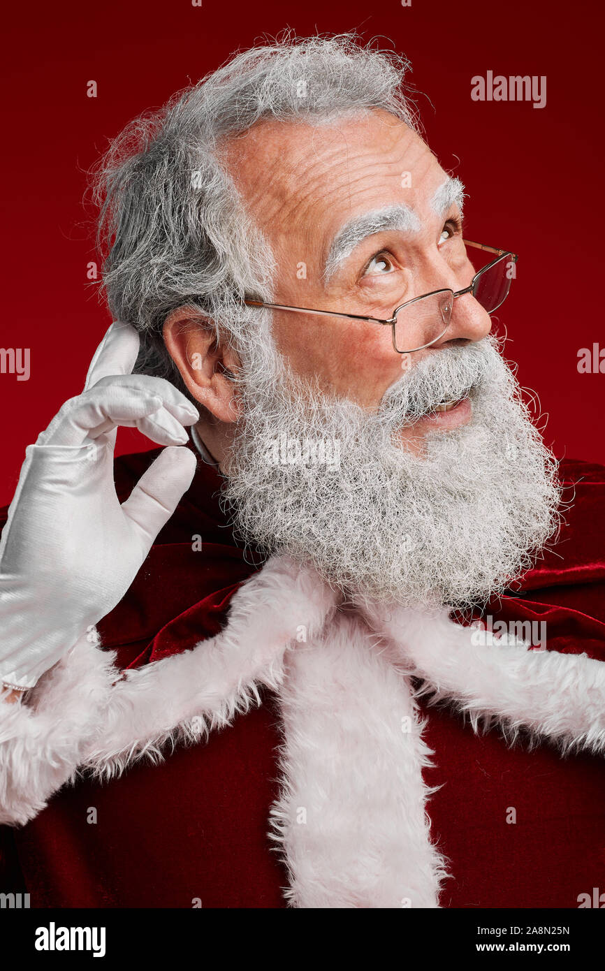 Head and shoulders portrait of pensive Santa Claus looking away while ...