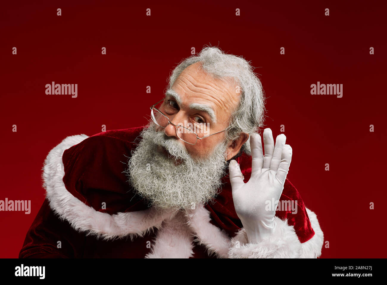 Portrait of classic Santa Claus putting hand to ear trying to hear ...