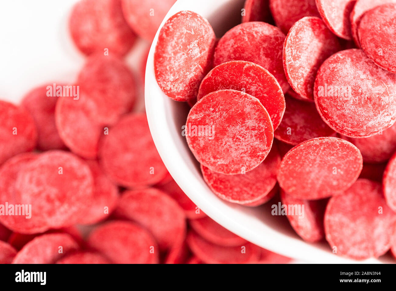 Red round chocolate chips for melting chocolate shapes on a white ...