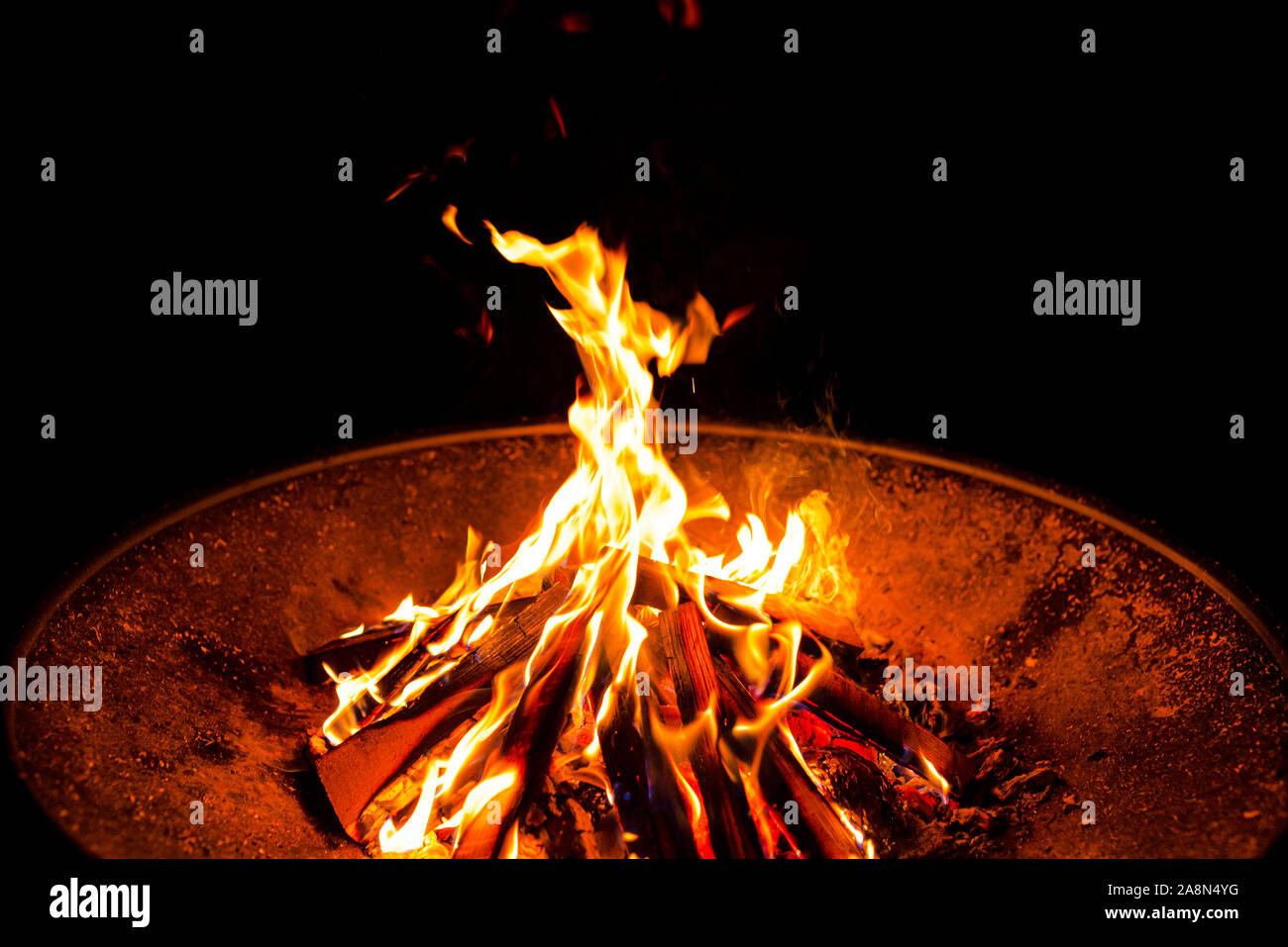 High flames from a burning wood fire on a metal grate at night Stock ...