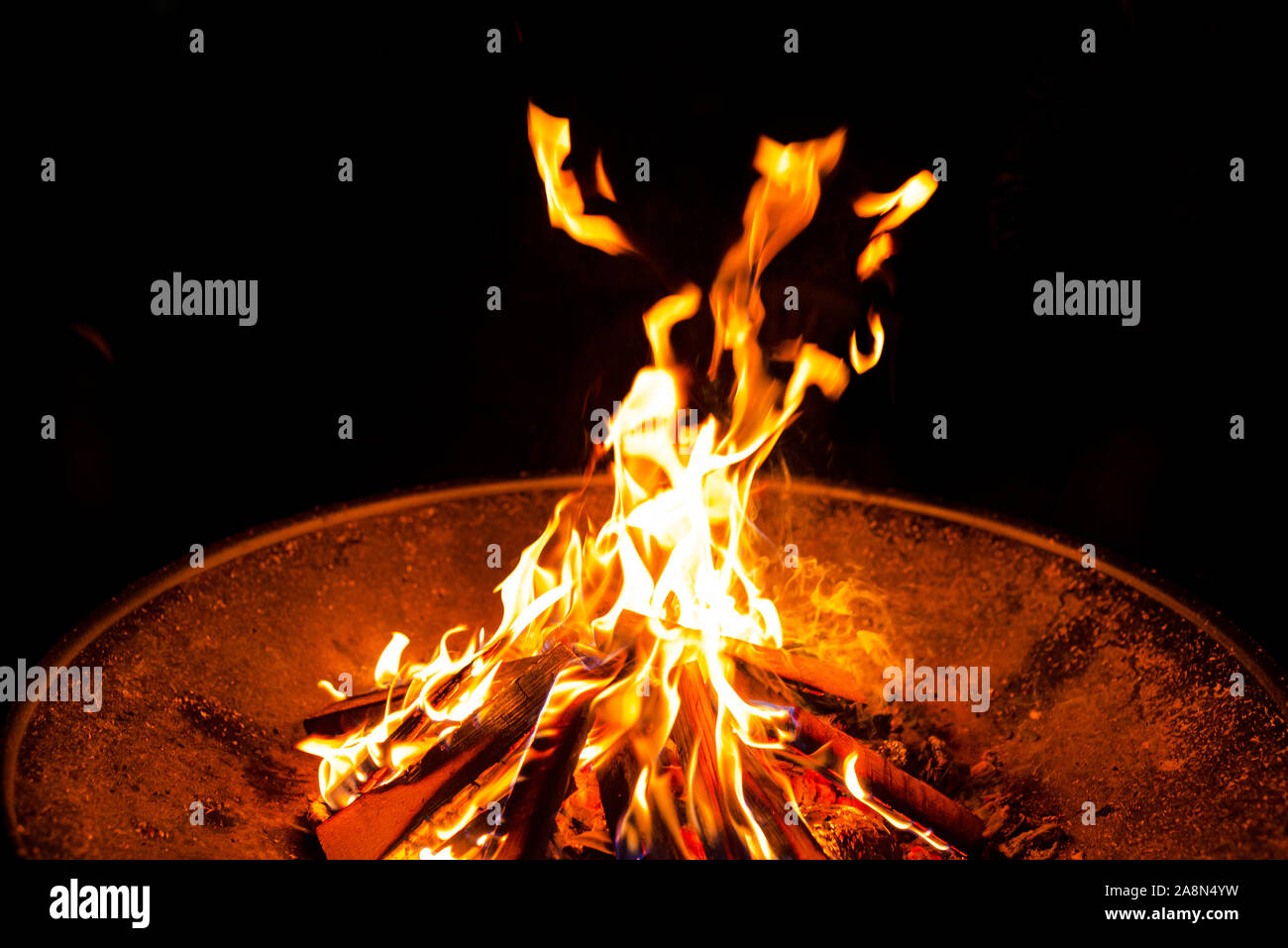 High flames from a burning wood fire on a metal grate at night Stock ...