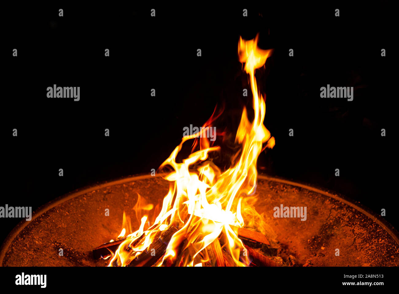 High flames from a burning wood fire on a metal grate at night Stock ...