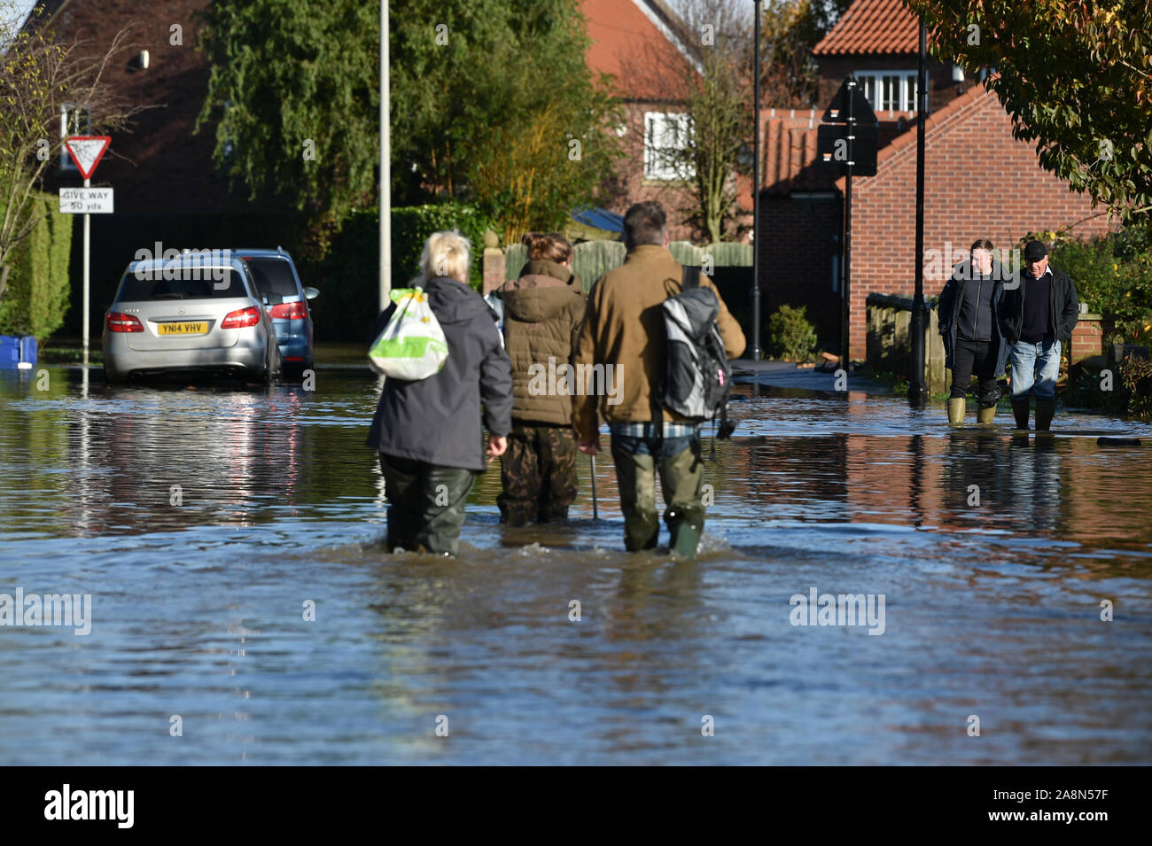 Residents wade through floodwater with their belongings in the village ...