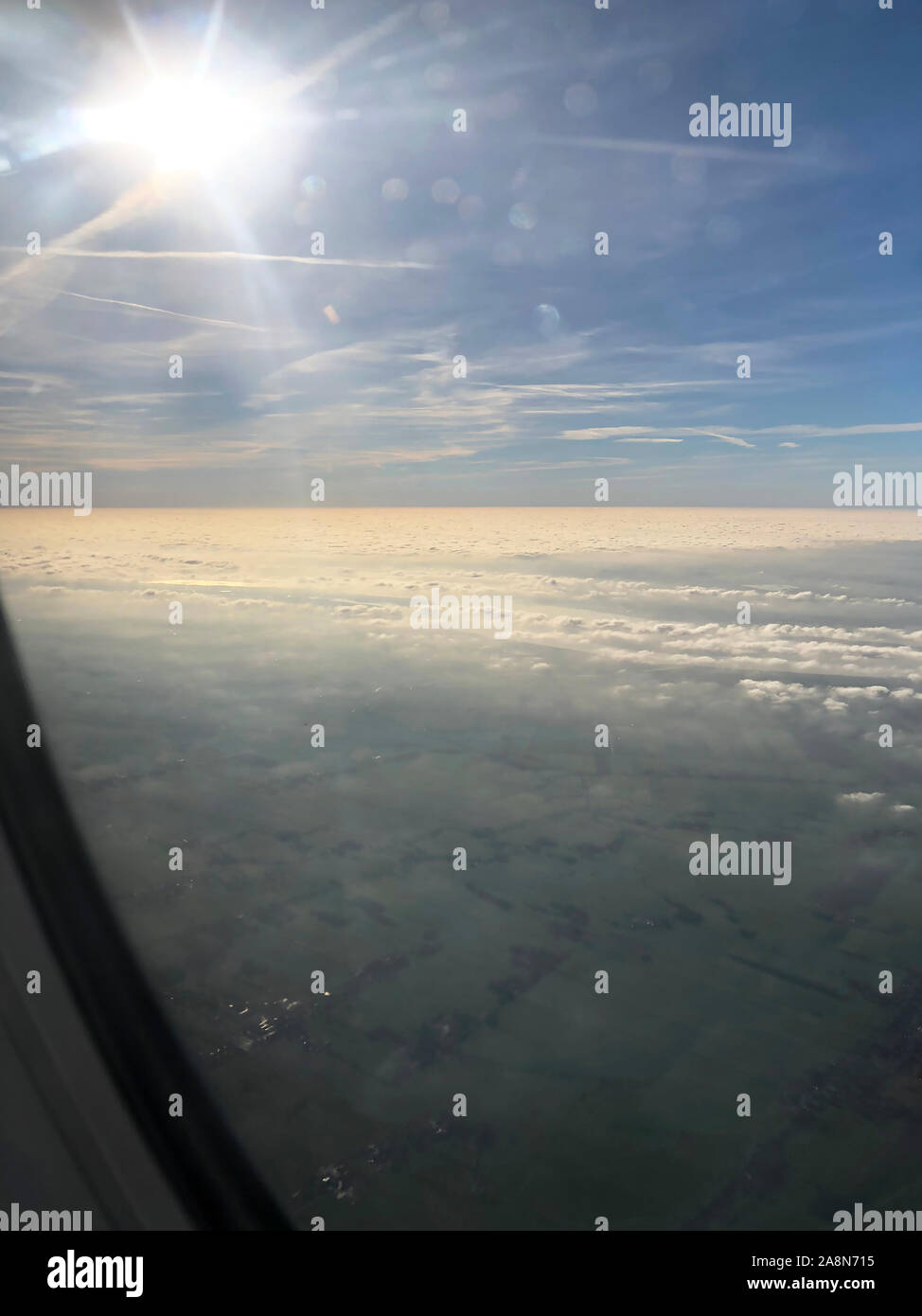 View of sun lens flare and clouds from window of a flying plane Stock ...