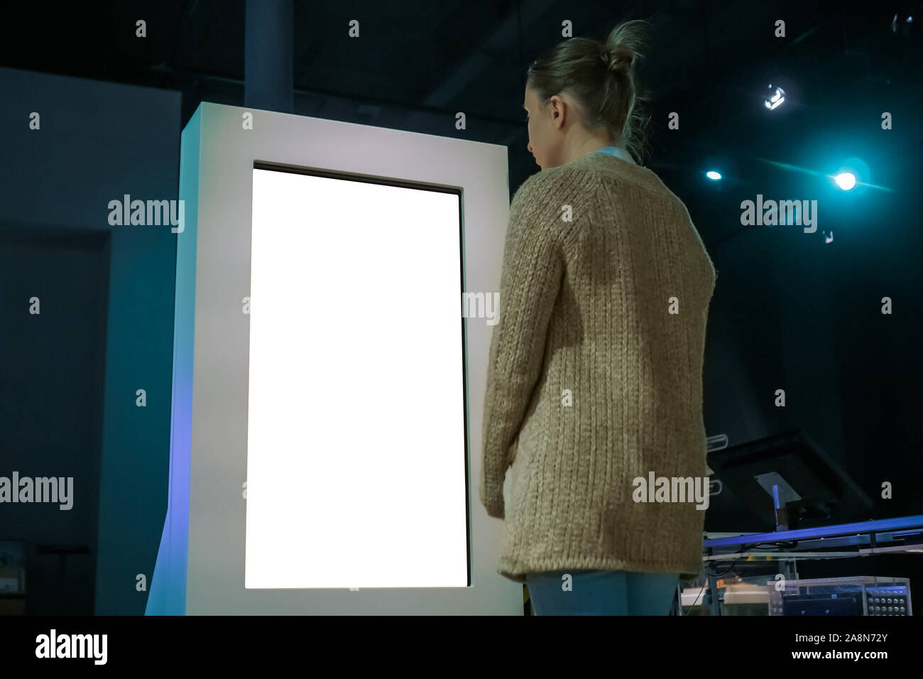 White screen concept - woman looking at blank white display kiosk at ...