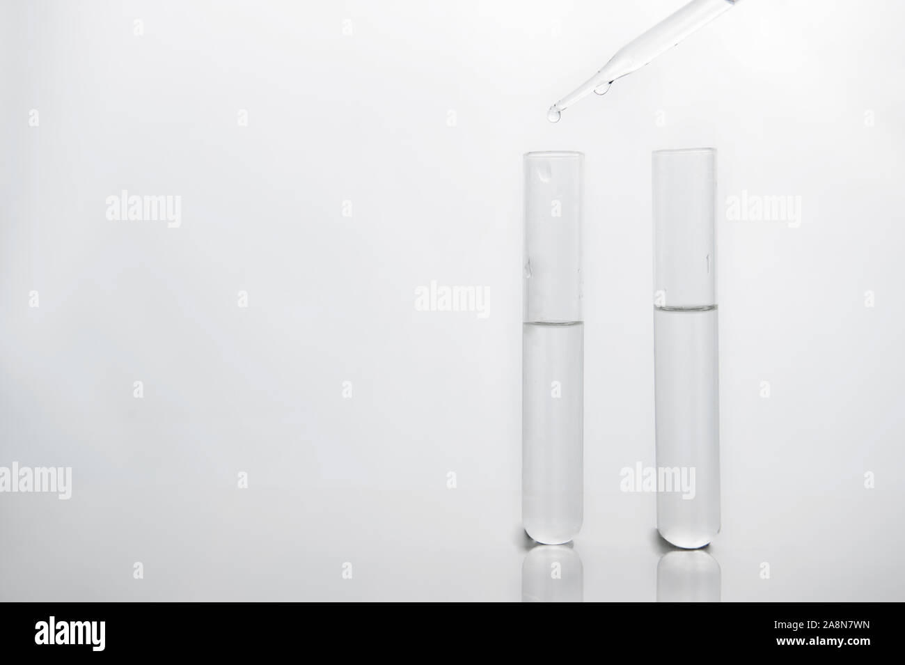 two glass test tube with drop of water from pipette on white clean ...