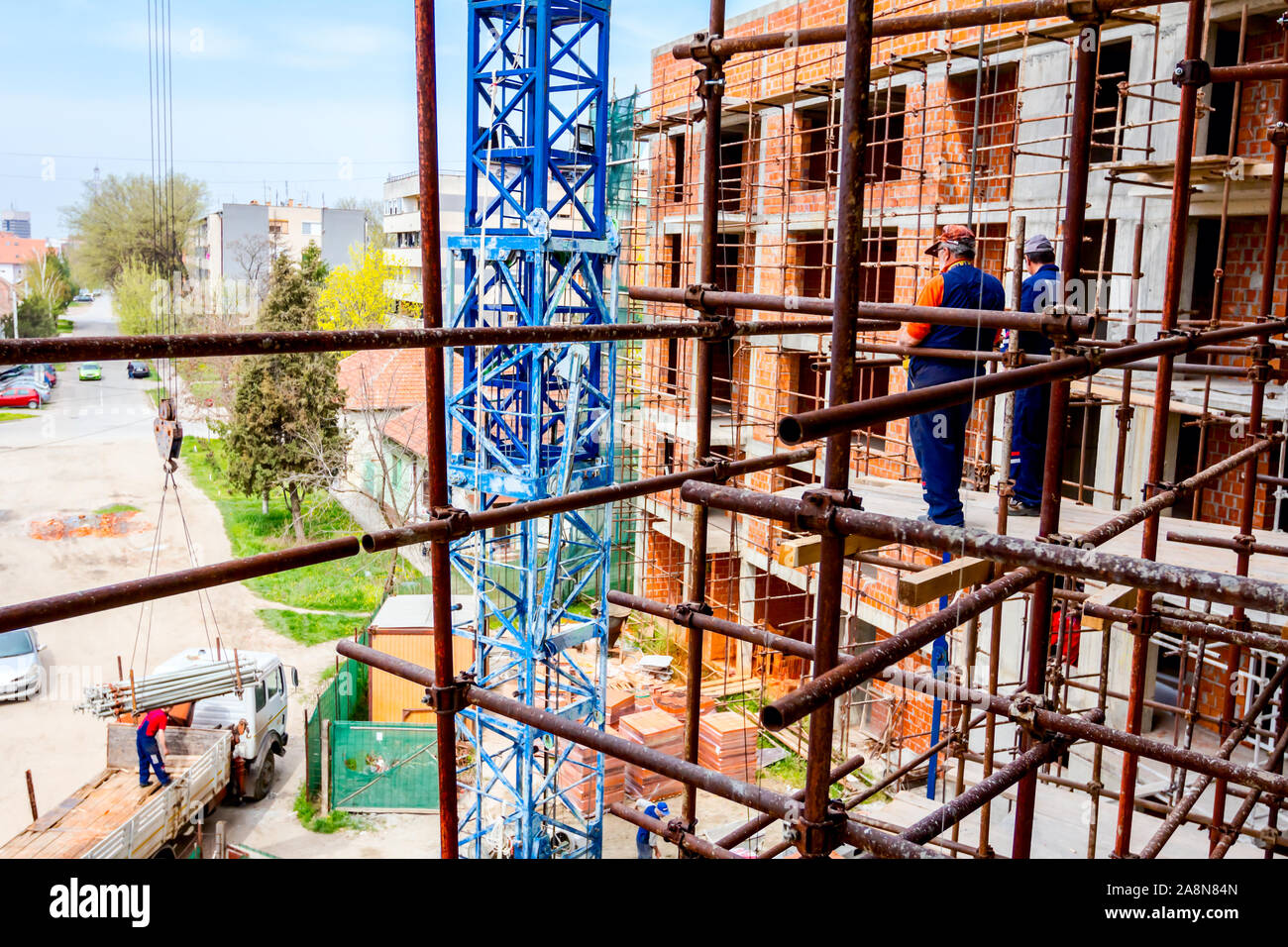 Riggers are standing on scaffold with wooden platform high up on ...