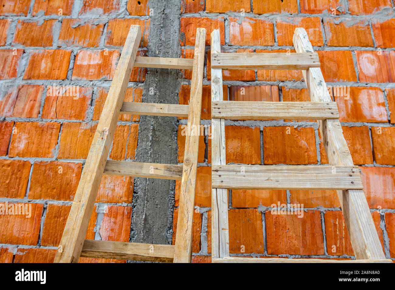 Front view on used wooden ladders, leaning against the wall for access ...