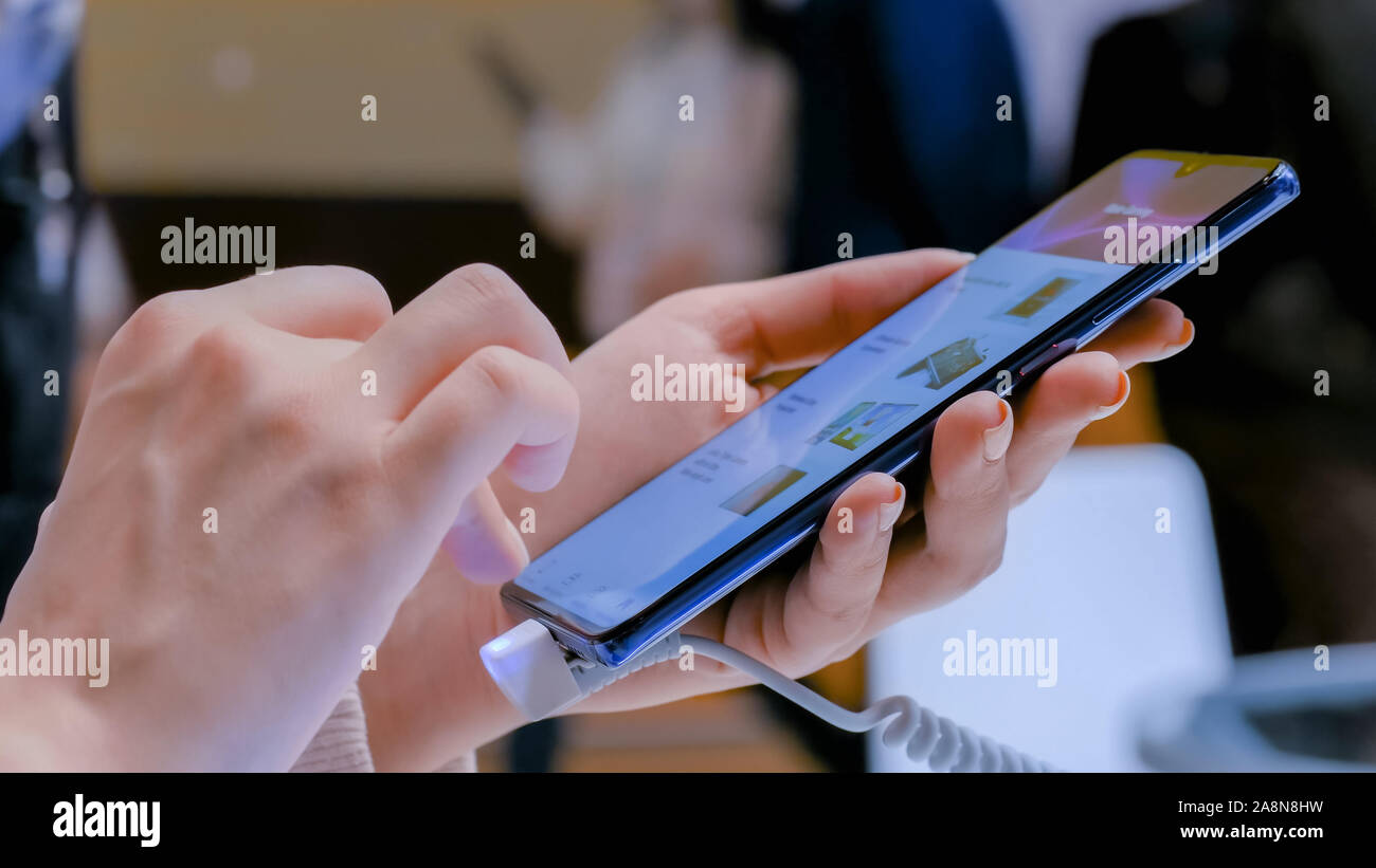 Woman customer testing new model of smartphone in electronic shop Stock ...