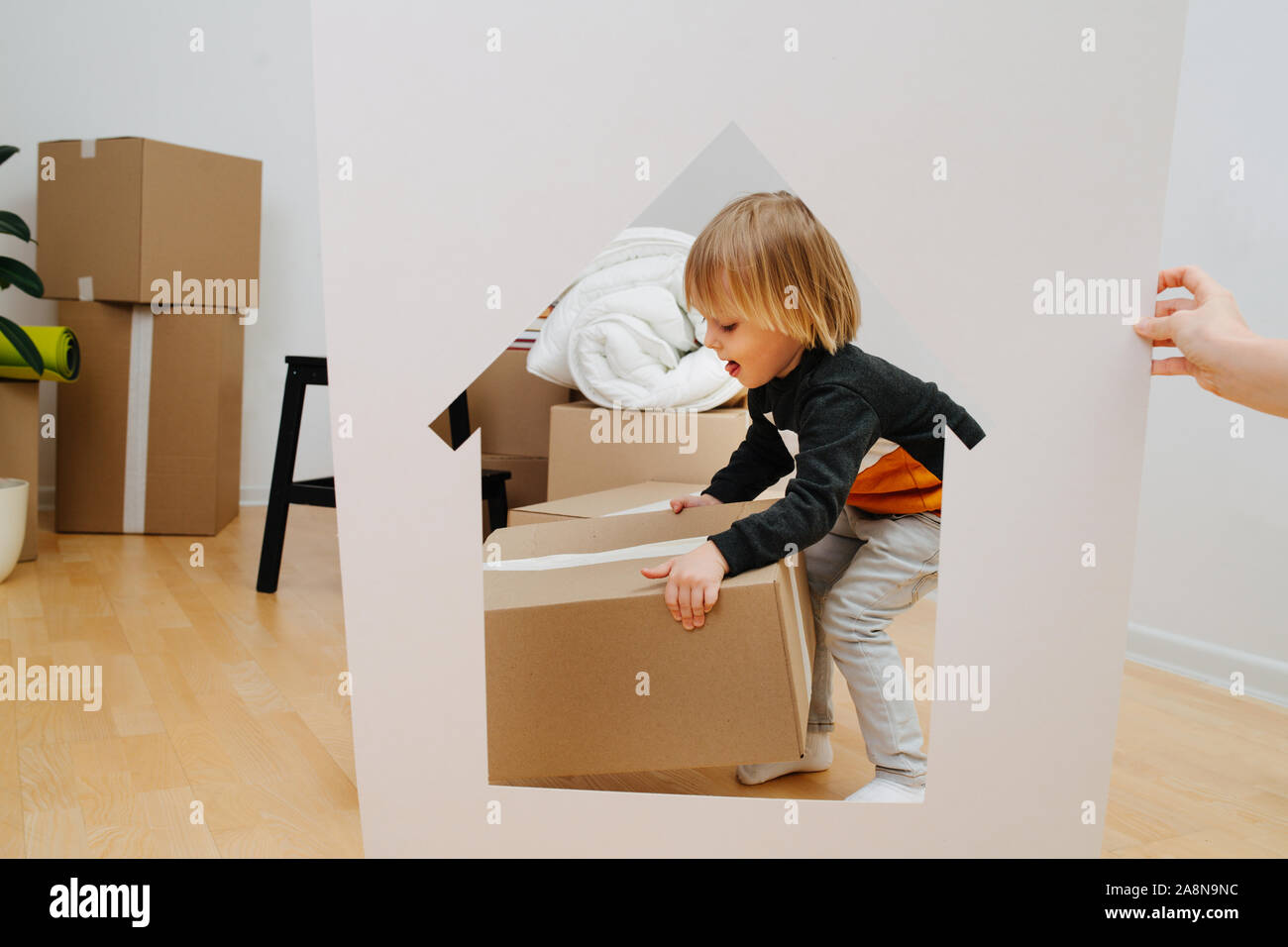Little boy lifting a box. Captured through house resembling frame Stock ...