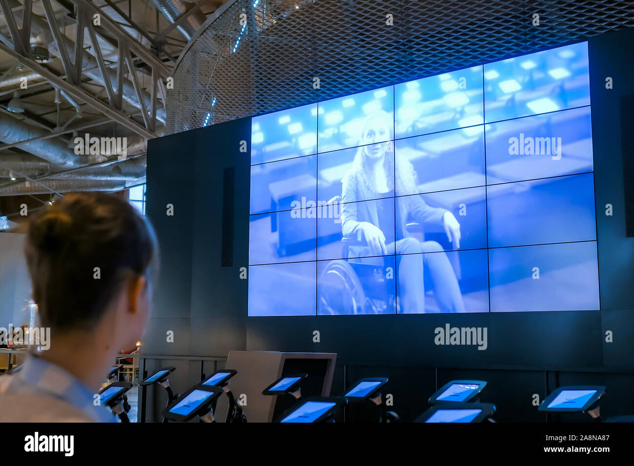 Woman watching video presentation about tolerance on large wall display ...