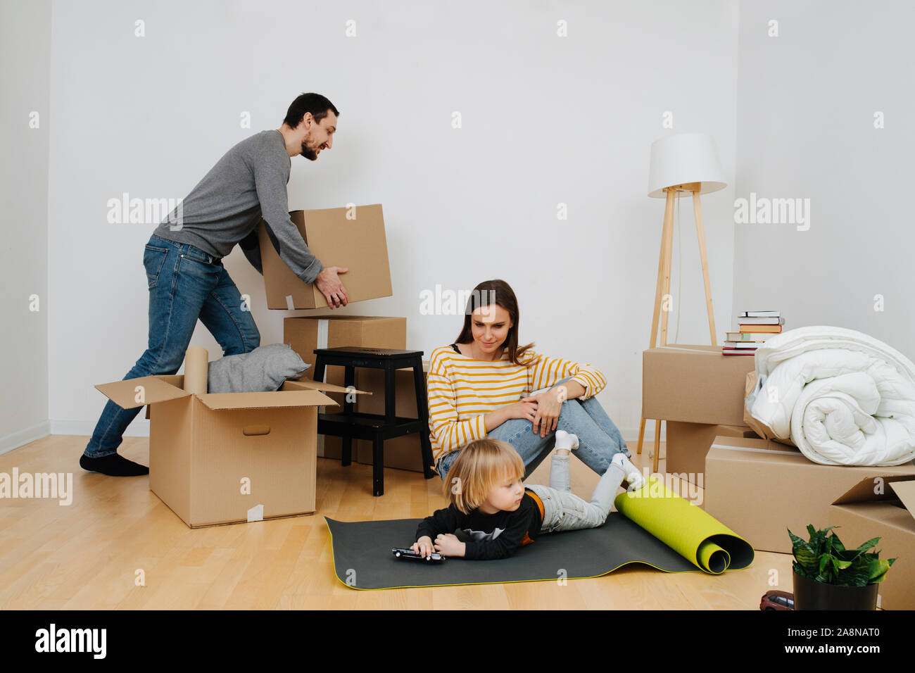 Happy family moving to a new home, boy plays with toys while parents ...