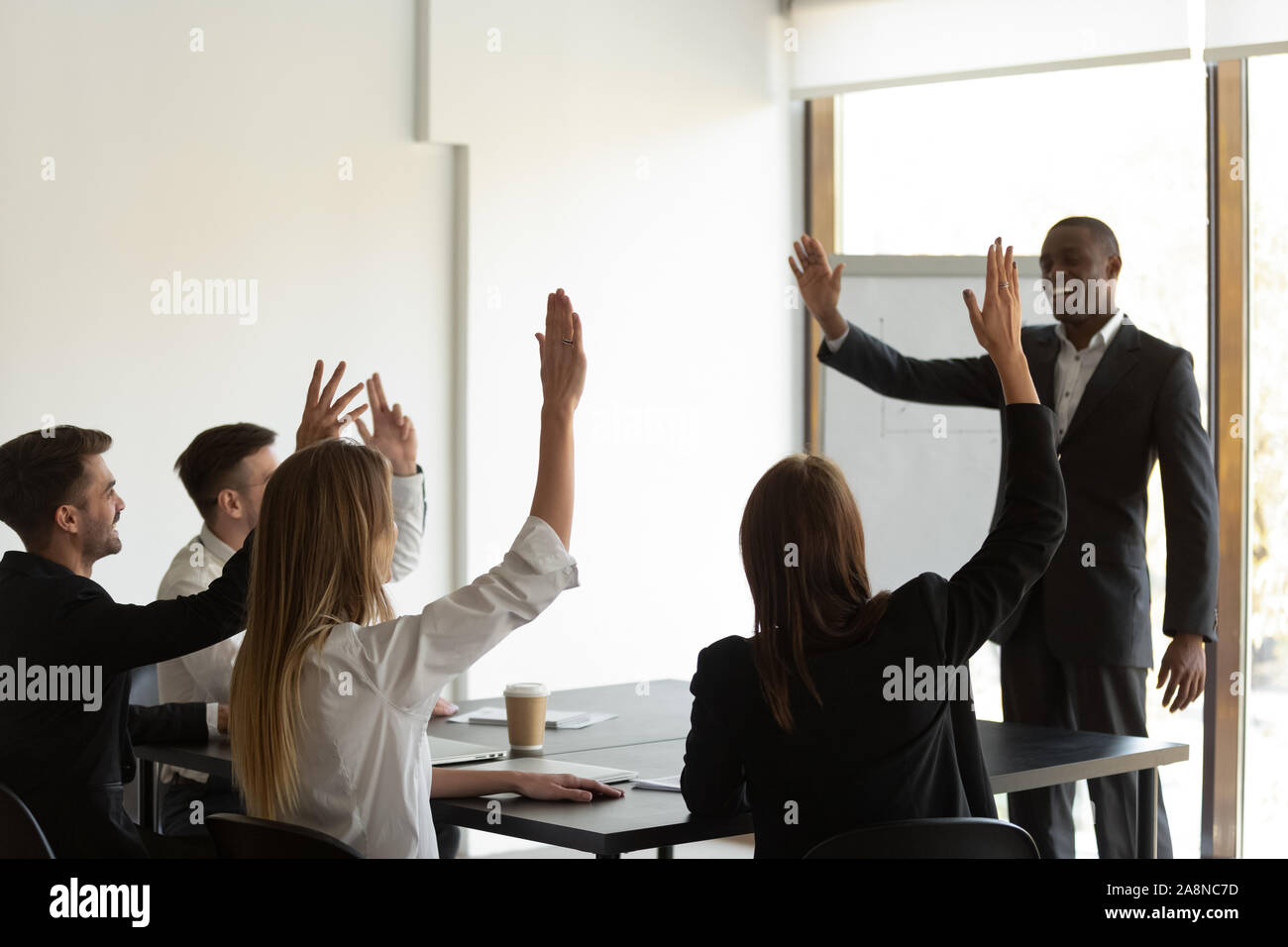 Diverse employees raise hands interacting with male coach Stock Photo ...