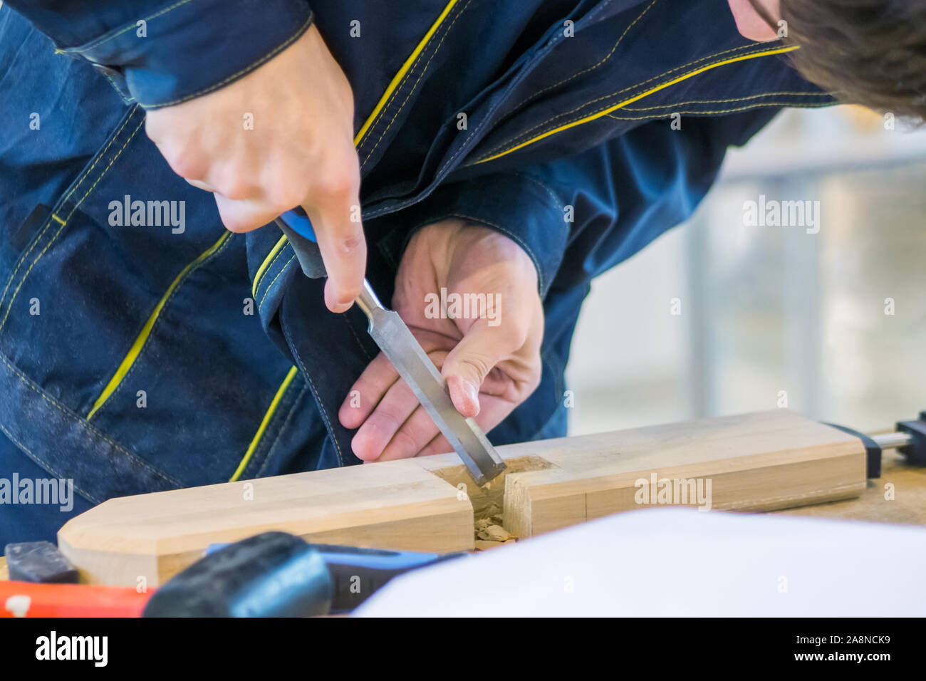 Carpenter using chisel to carve wood on rough workbench at workshop ...