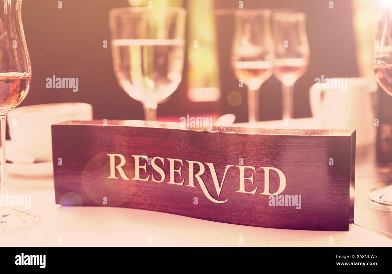 Wooden reserved plate on an arranged restaurant table, toned image ...