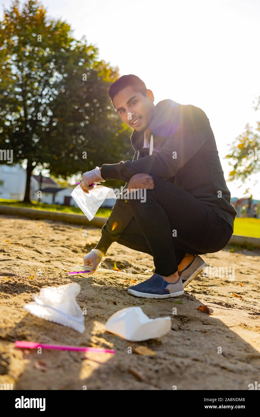 Back lit of man cleaning garbage on sand at park Stock Photo - Alamy
