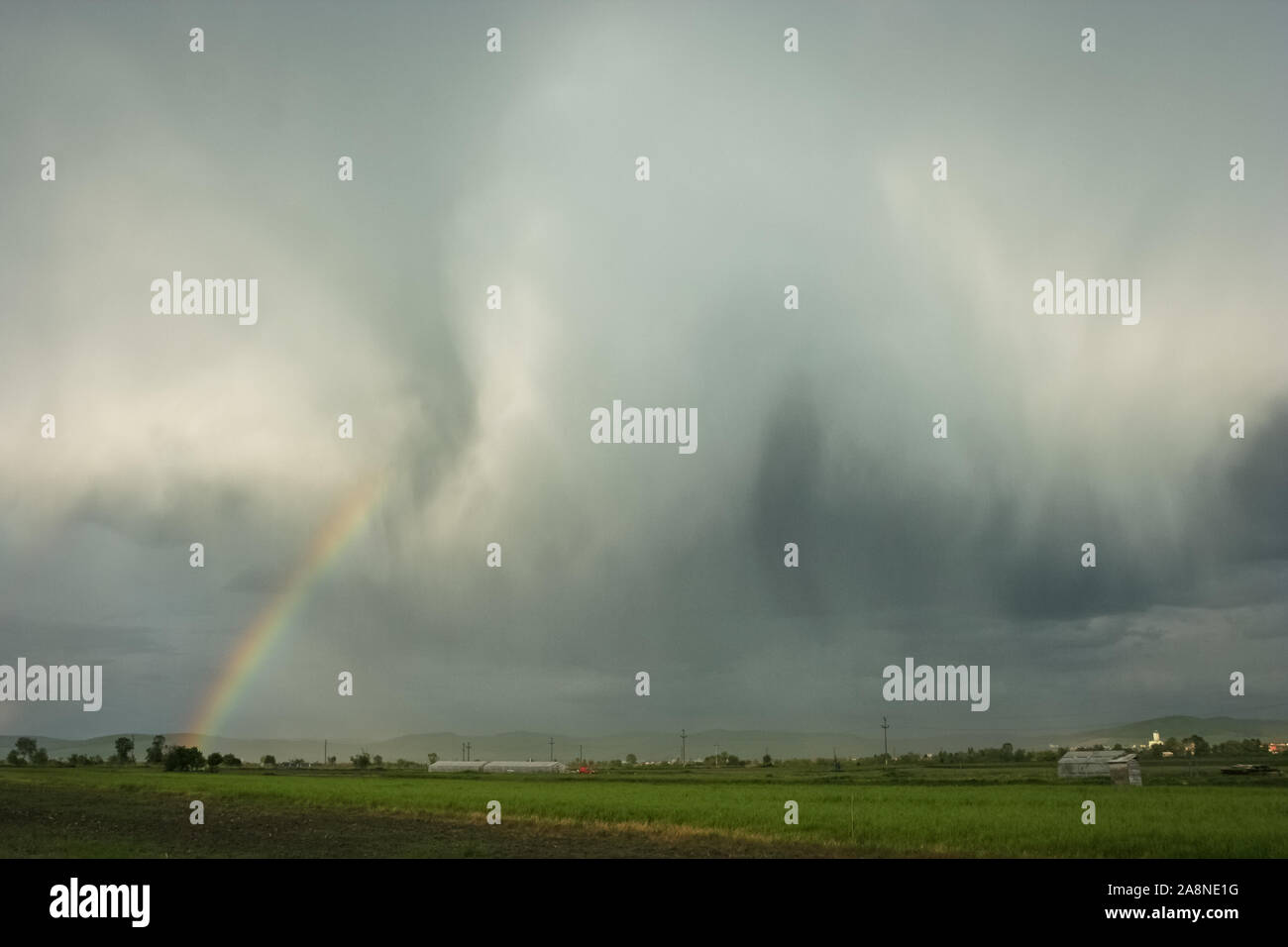 Bright colorful rainbow while a spectacular shower with rain and hail ...