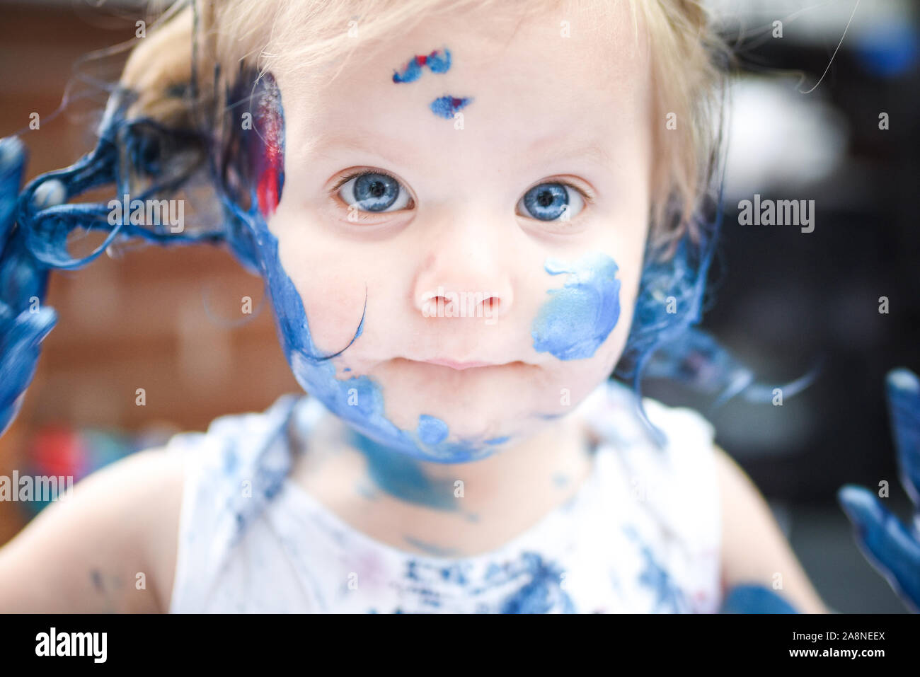 An adorable little toddler, girl has fun playing with colouring paints ...