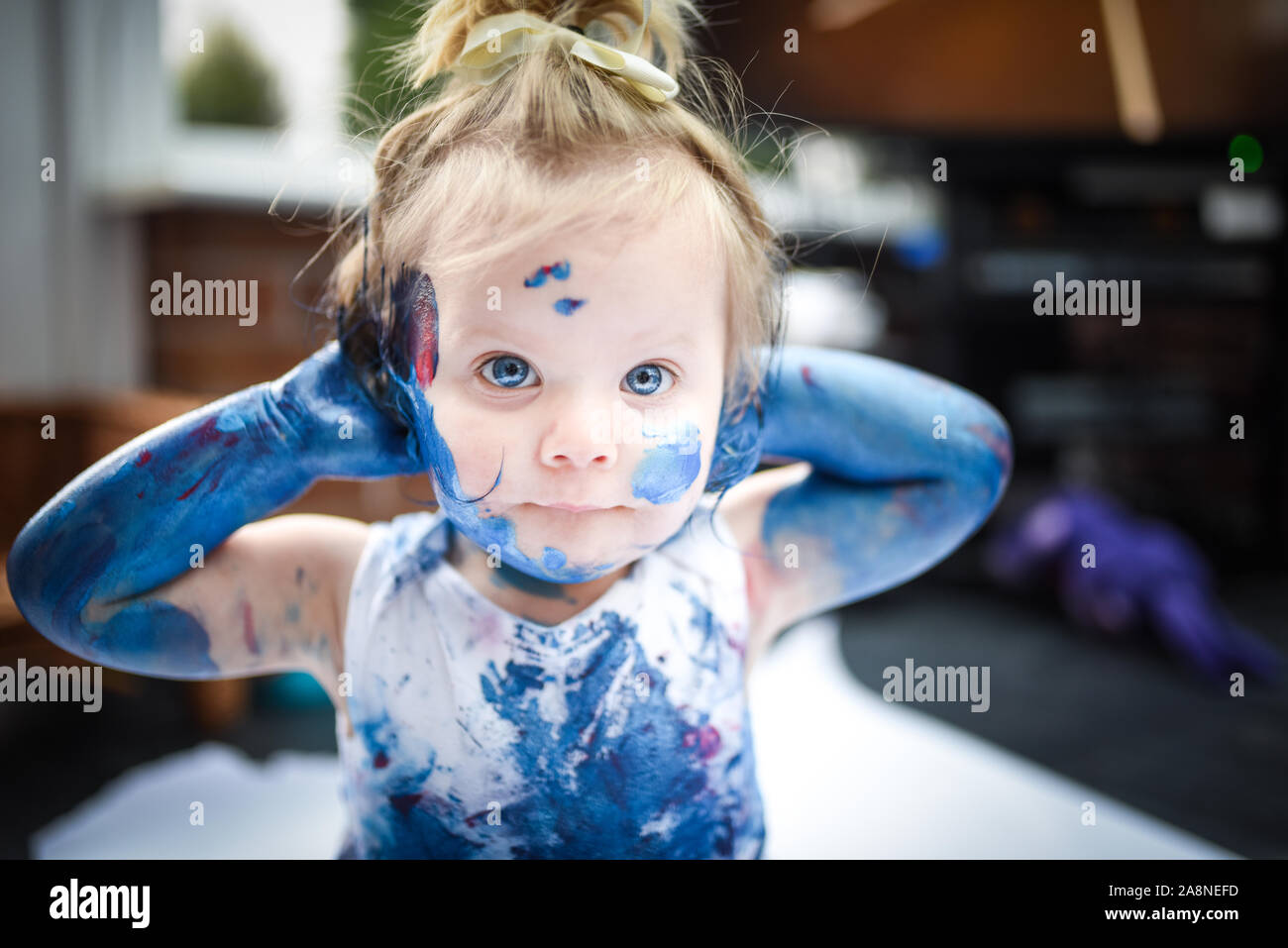 An adorable little toddler, girl has fun playing with colouring paints ...