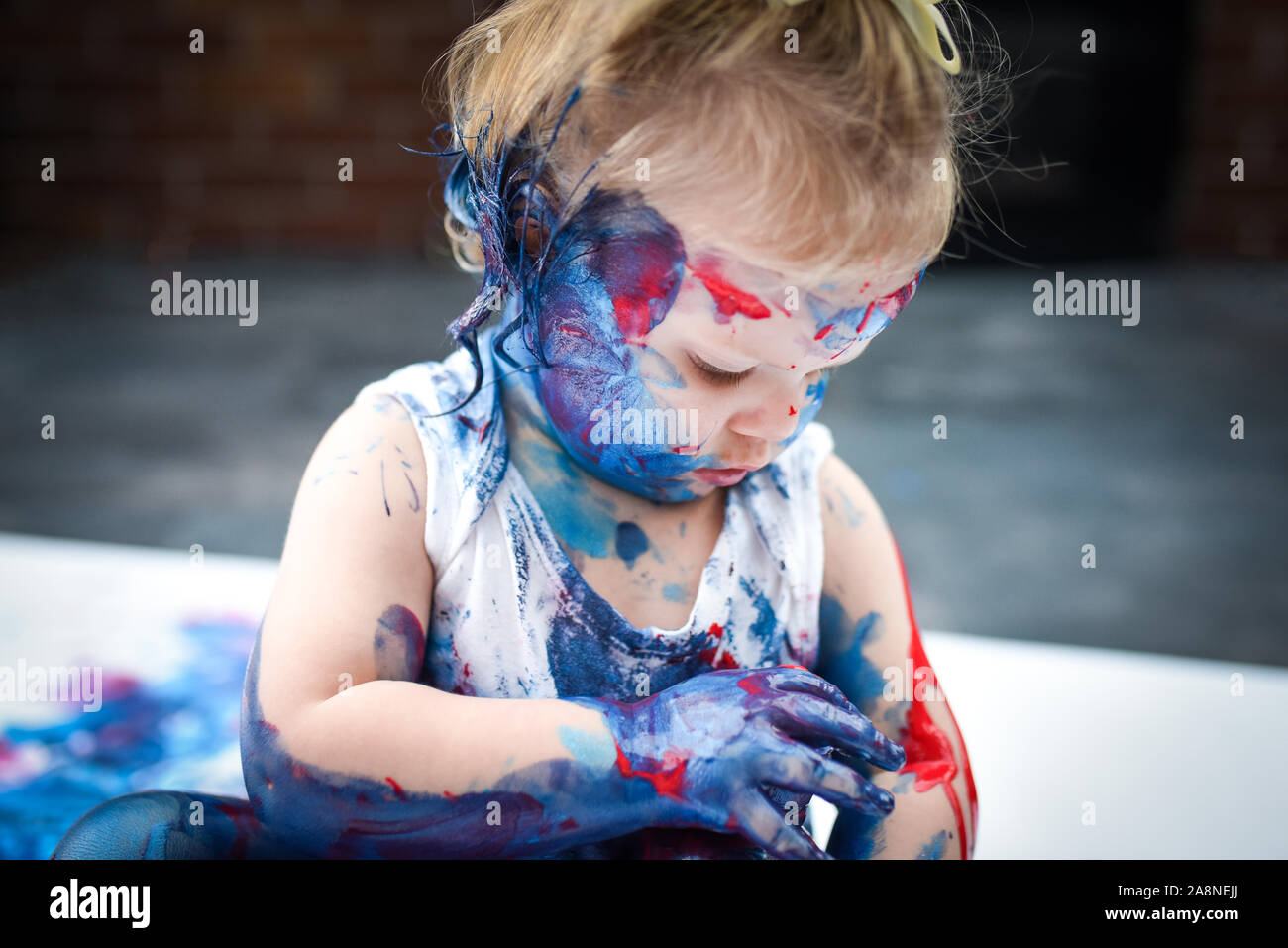 An adorable little toddler, girl has fun playing with colouring paints ...