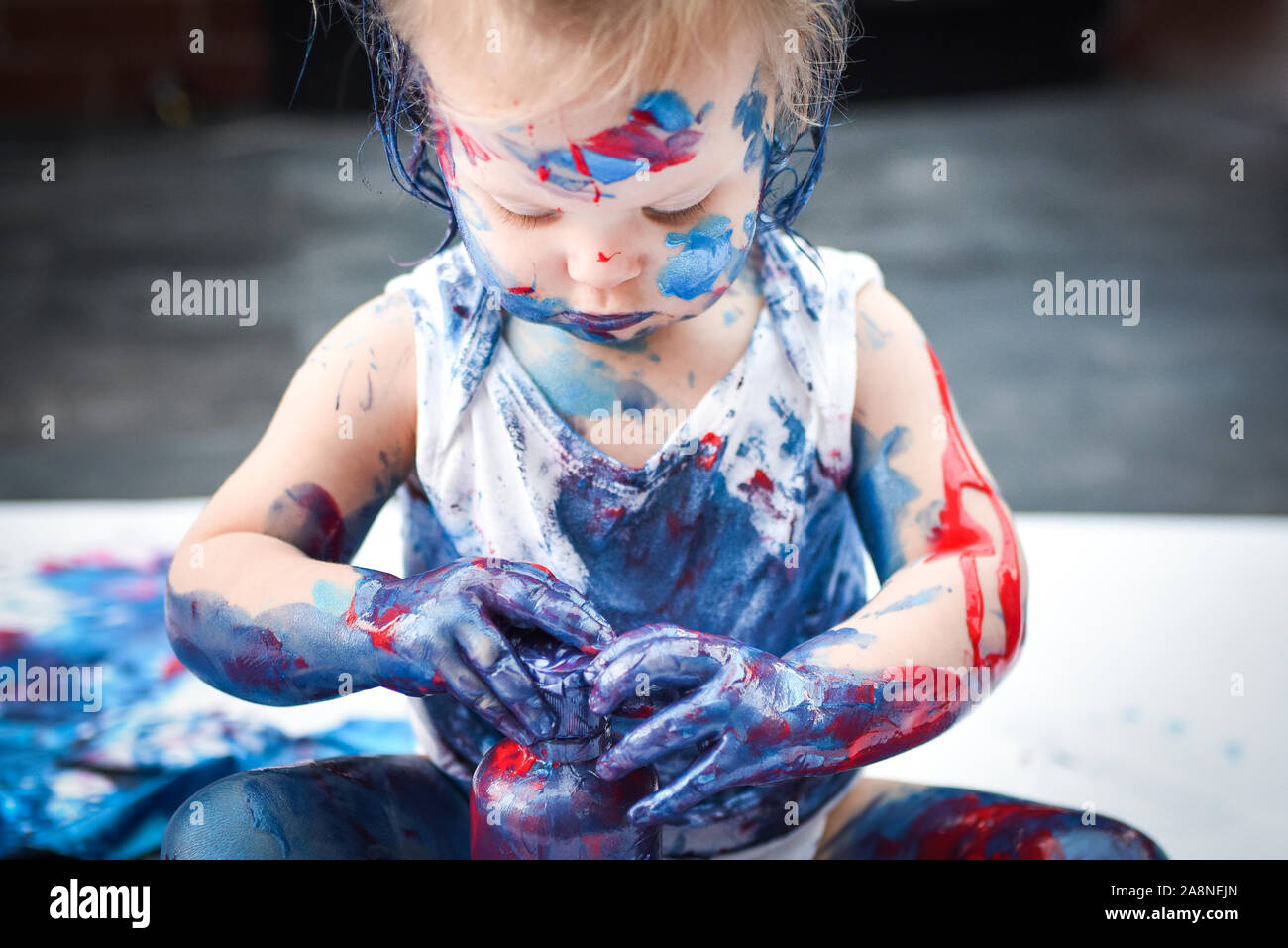 An adorable little toddler, girl has fun playing with colouring paints ...