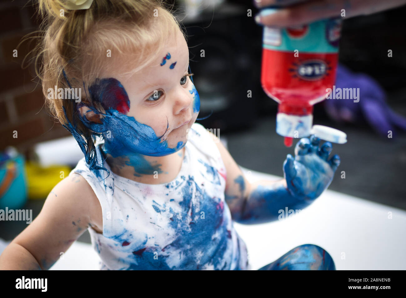 An adorable little toddler, girl has fun playing with colouring paints ...
