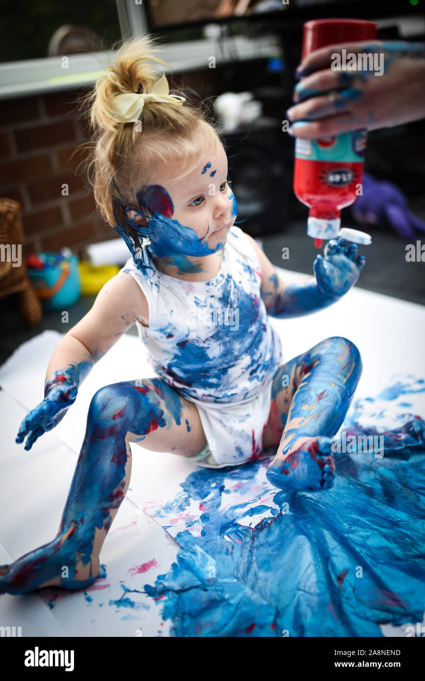 An adorable little toddler, girl has fun playing with colouring paints ...