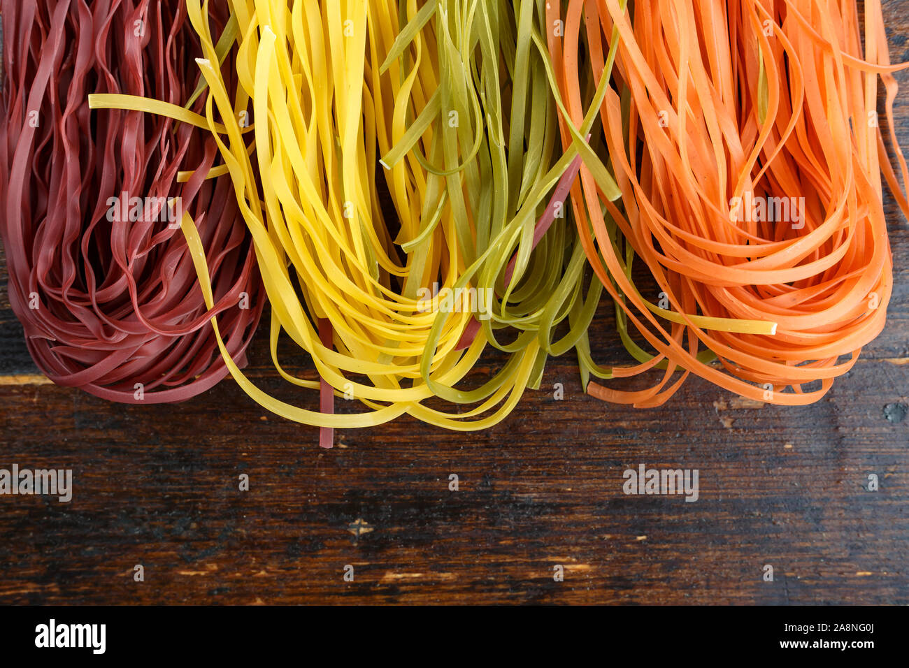 multi-colored long spaghetti. traditional italian pasta on a wooden background. place for text ...