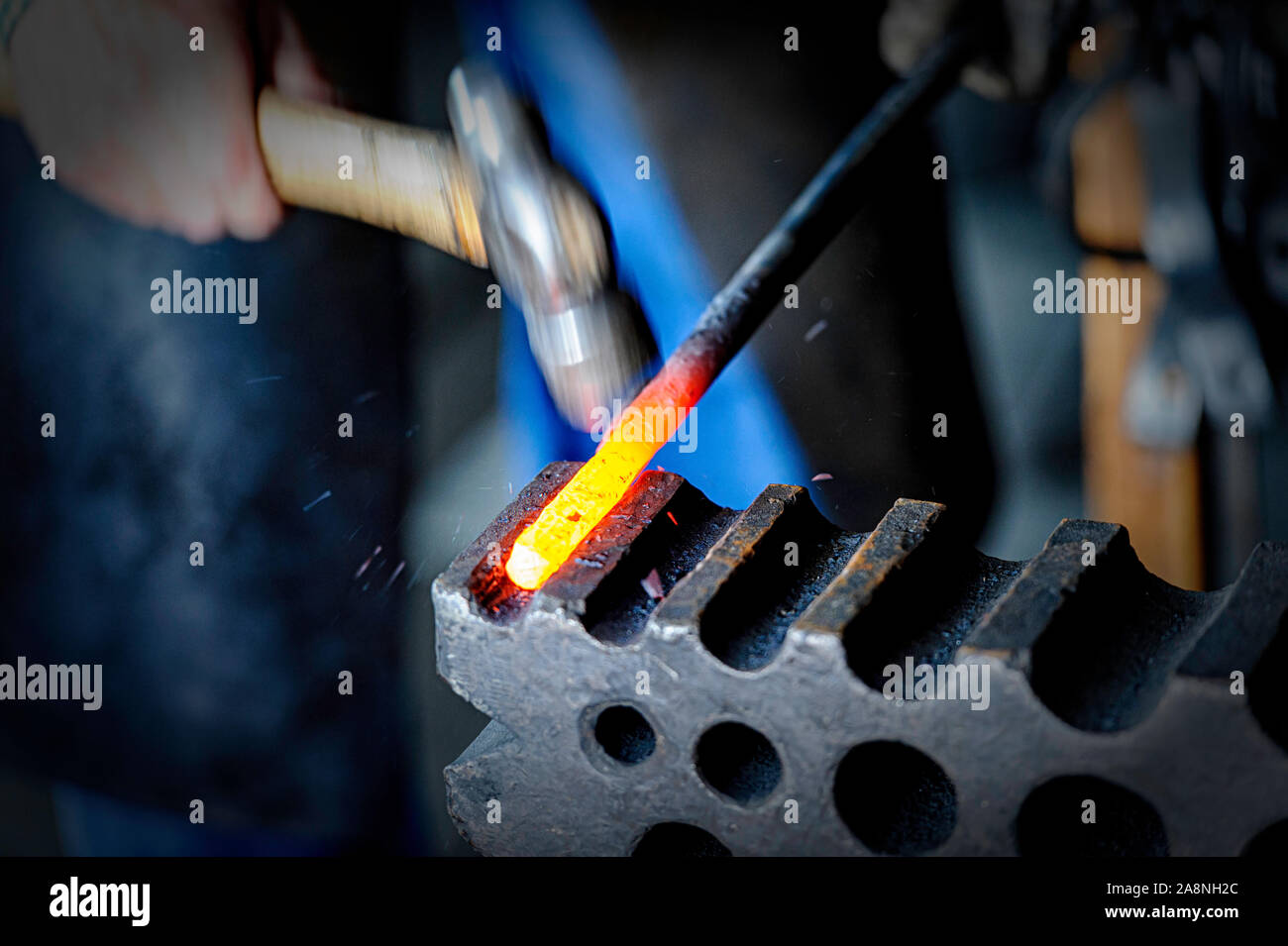 Blacksmith hammering and shaping a red hot iron bar Stock Photo - Alamy
