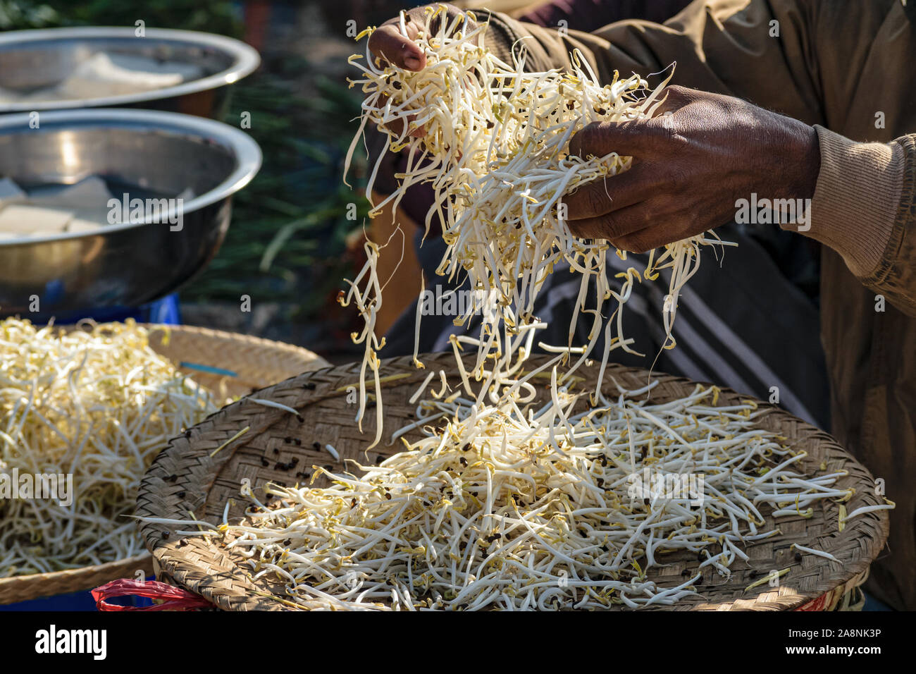 A man tossing fresh soy bean sprouts at the local food market in Kalaw ...