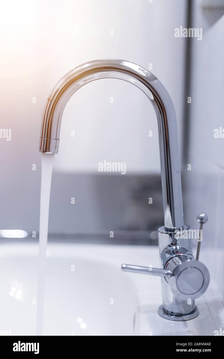 Close up of a water spigot in a clean bathroom. Water saving, sunlight ...