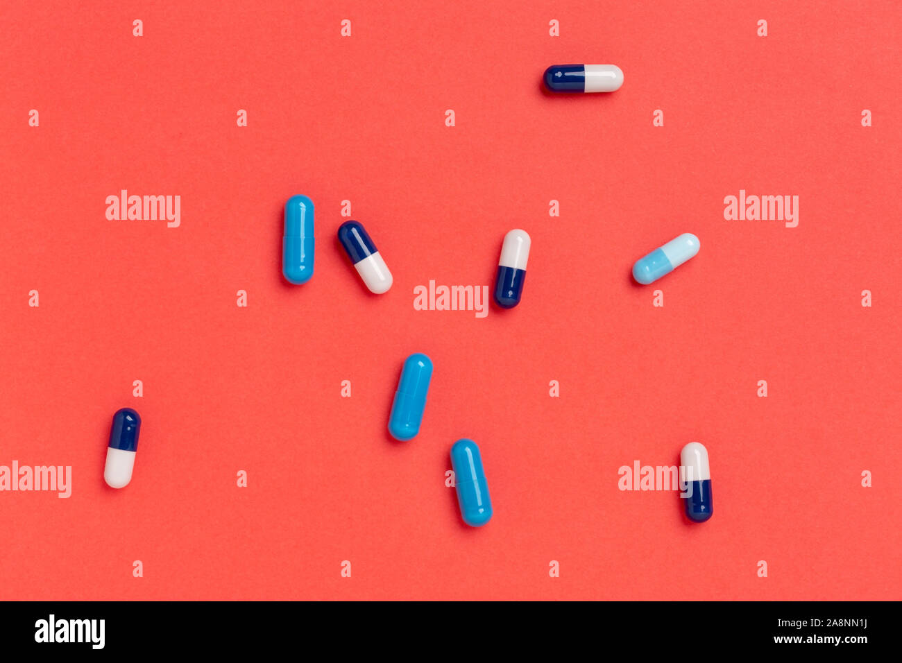 Blue drug capsules on a red color background Stock Photo - Alamy
