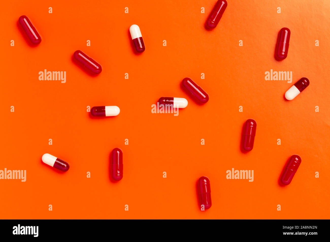Red drug capsules on a red color background Stock Photo - Alamy