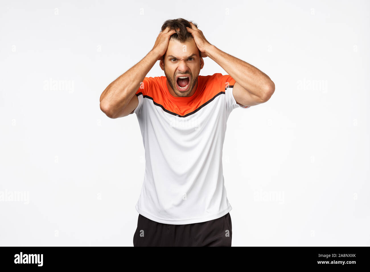 Angry, aggressive mascular sportsman looking furious, grab head in rage ...