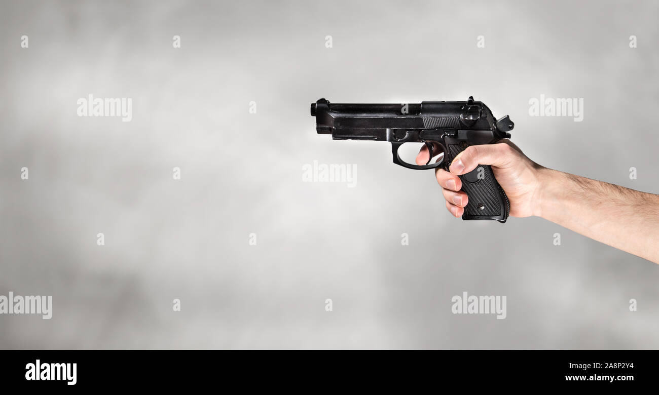 hand with gun on grey background Stock Photo - Alamy