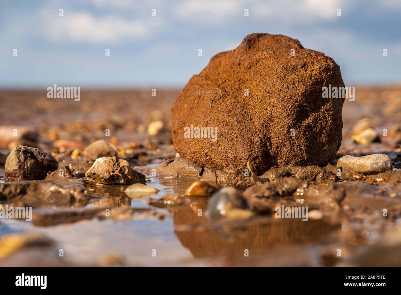 A large stone surrounded by smaller stones in Snettisham Beach, Norfolk ...