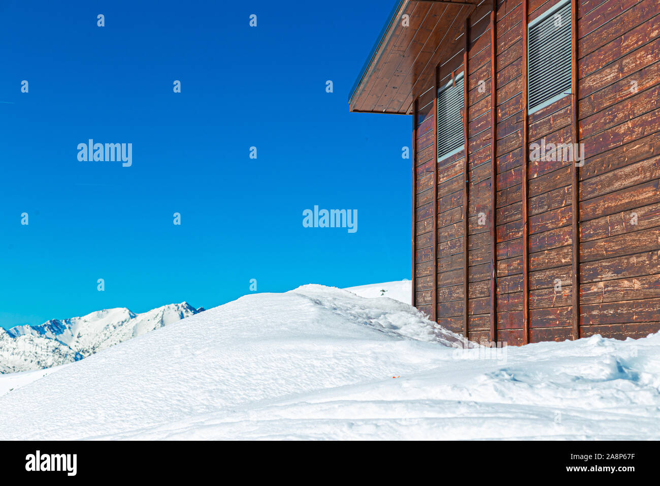 Wall of a wooden house in the mountains in the snow. Winter day at a ...