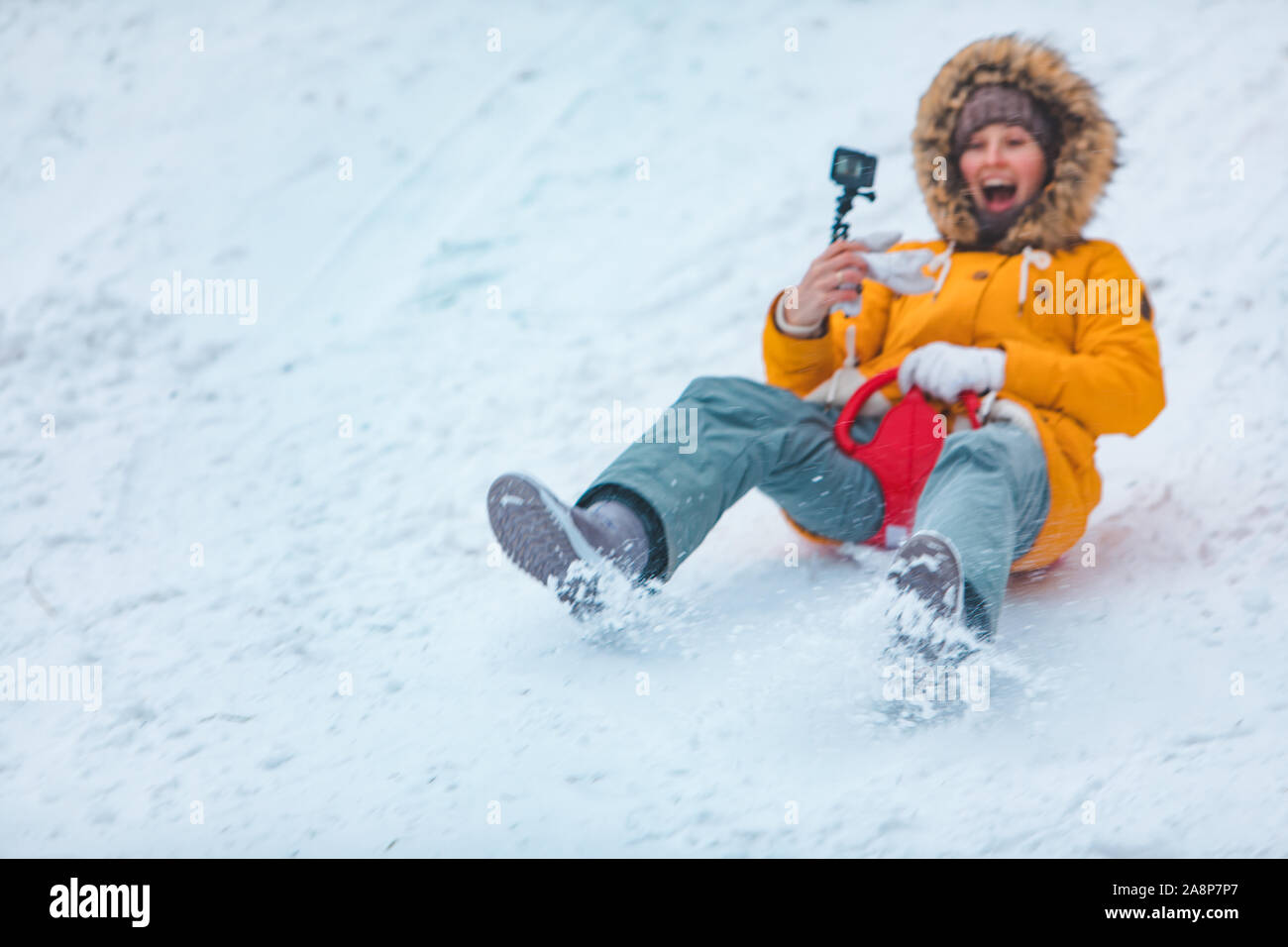 young woman sliding down by snowed hill Stock Photo - Alamy