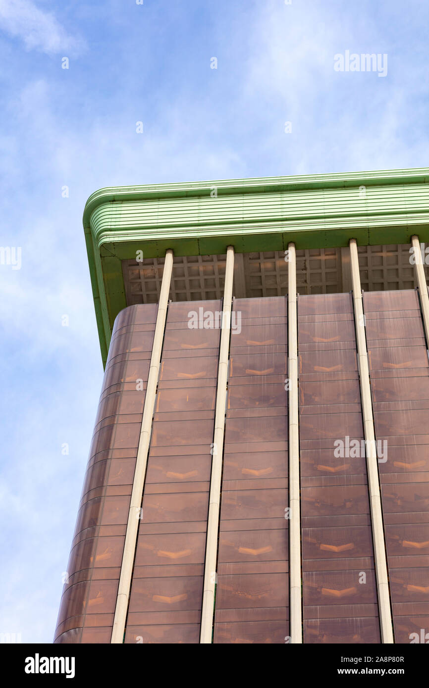 bronze glass building with the green roof top on a blue sky with clouds ...