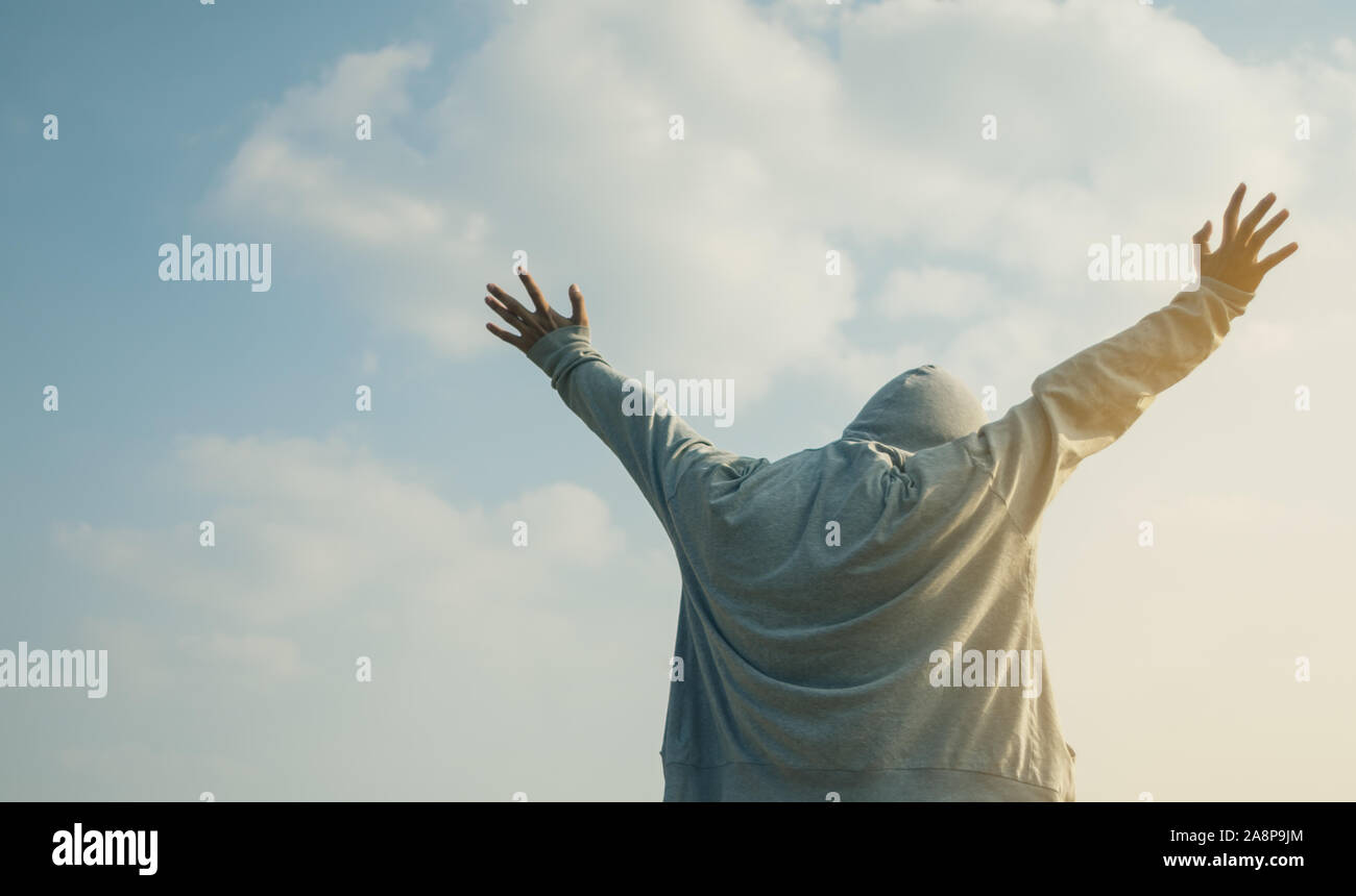 Alone man standing and raise his hand against morning light Stock Photo ...