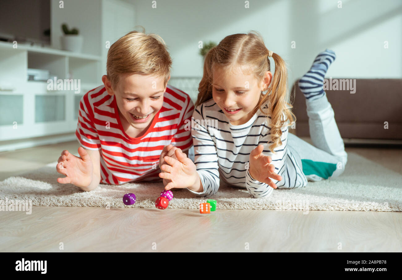 Portrait of two cheerful children laying on the floor and playing ...