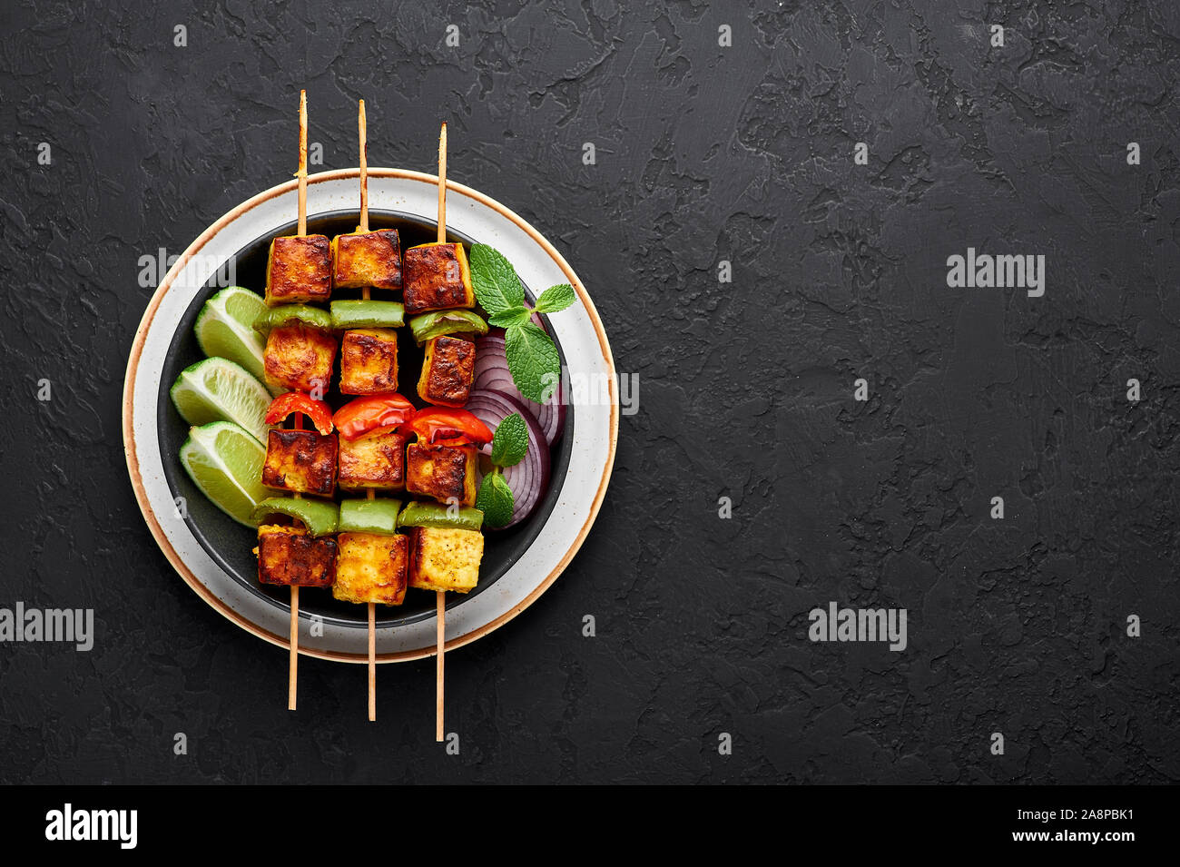 Paneer Tikka at skewers in black bowl at dark slate background. Paneer ...
