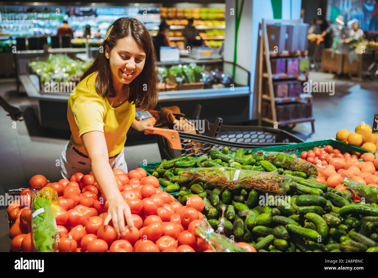 woman choosing red tomatoes from store shelf grocery shopping Stock ...