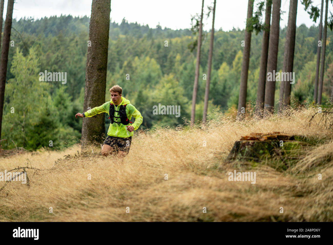 A young athlete in barefoot shoes runs down the mountain. Mountain run ...