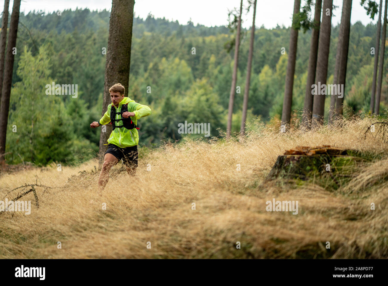 A young athlete in barefoot shoes runs down the mountain. Mountain run ...