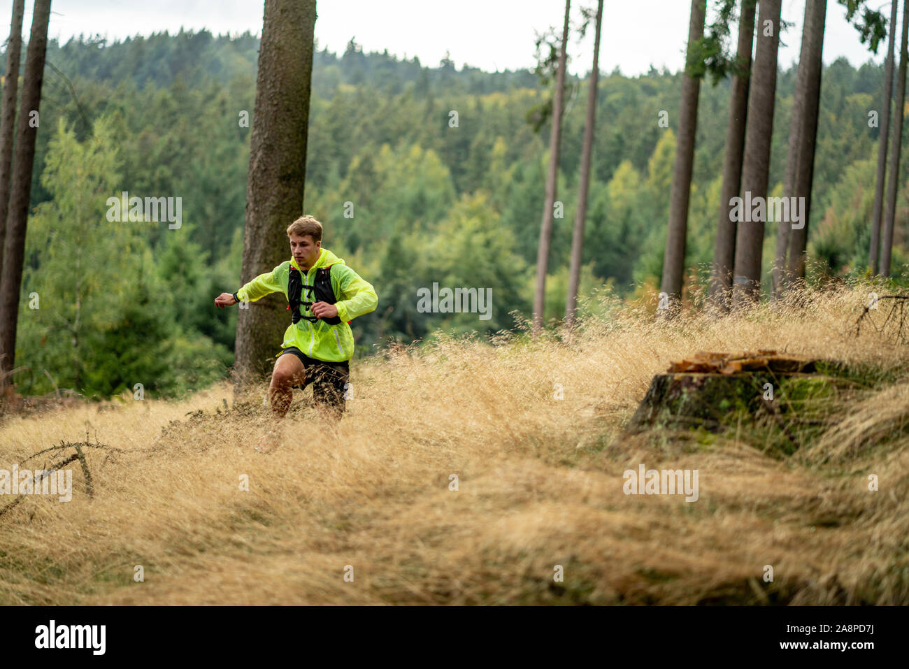 A young athlete in barefoot shoes runs down the mountain. Mountain run ...