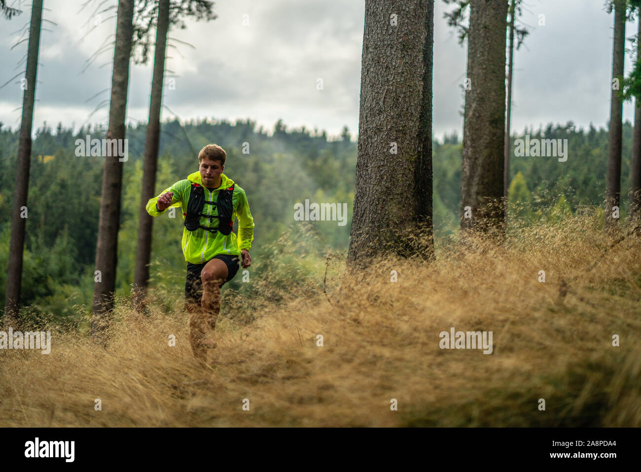 A young athlete in barefoot shoes runs down the mountain. Mountain run ...
