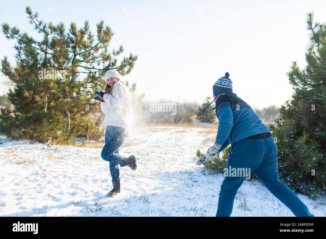 Loving couple play snowballs in winter in the forest. Throw each other ...