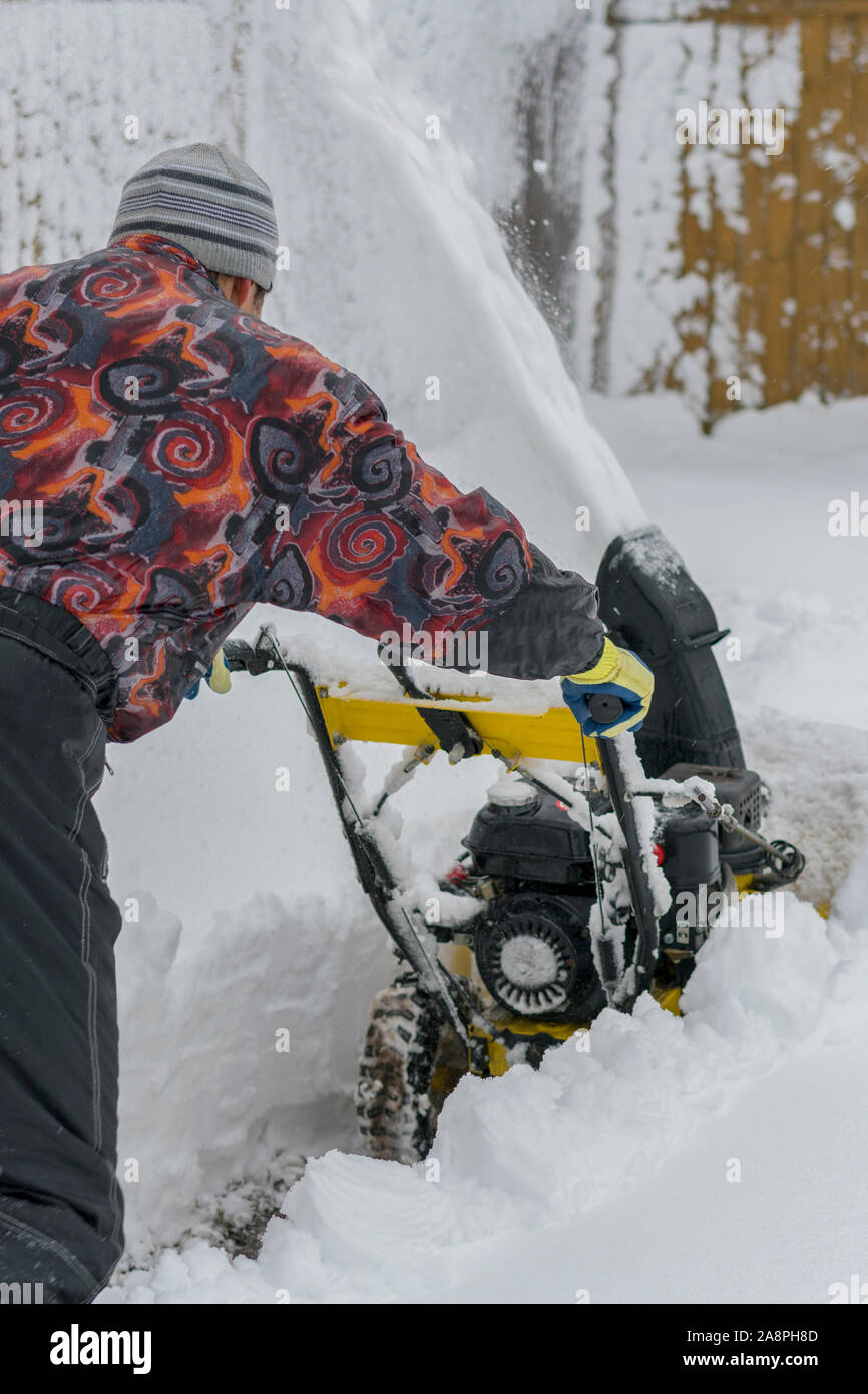 man operating snow blower to remove snow on driveway. Man using a ...