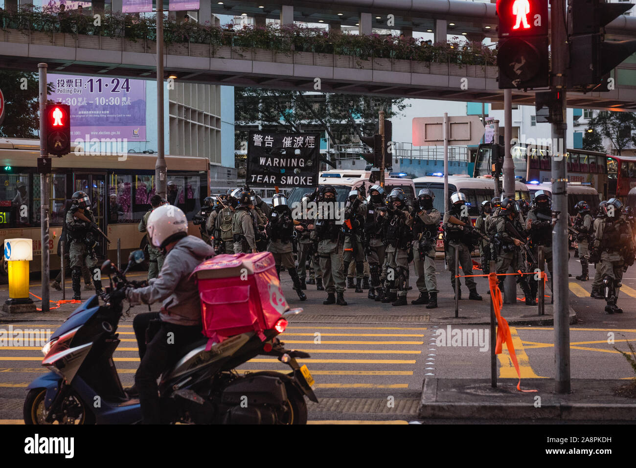 A food delivery man stops close to riot police during the ...